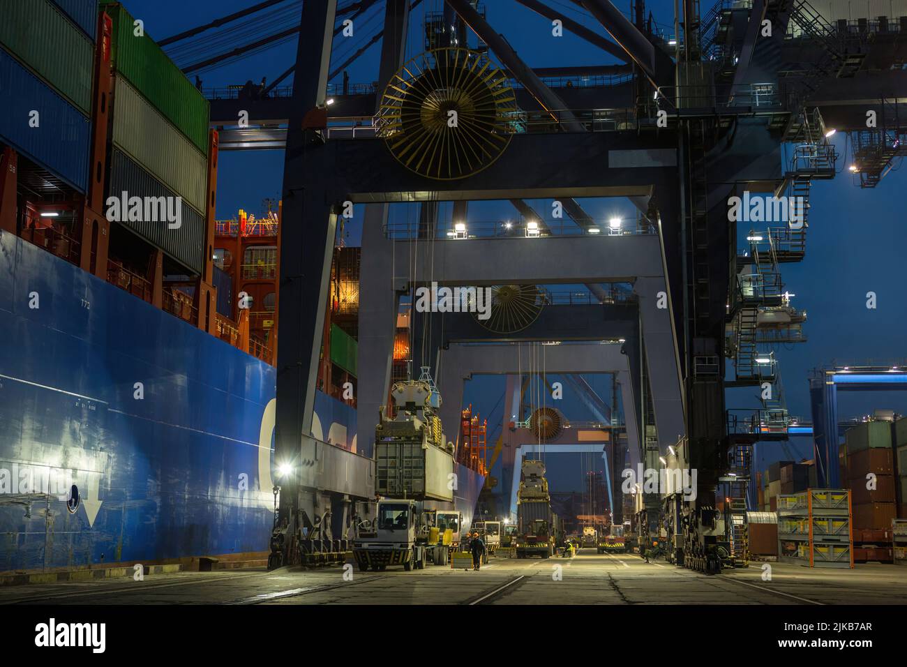operation of container terminal at night. Unloading container ship at night. Mooring cranes ...