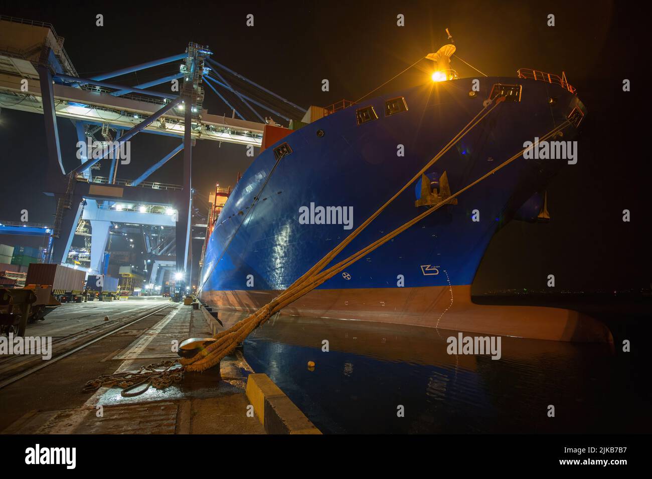 operation of container terminal at night. Unloading container ship at night. Mooring cranes ...