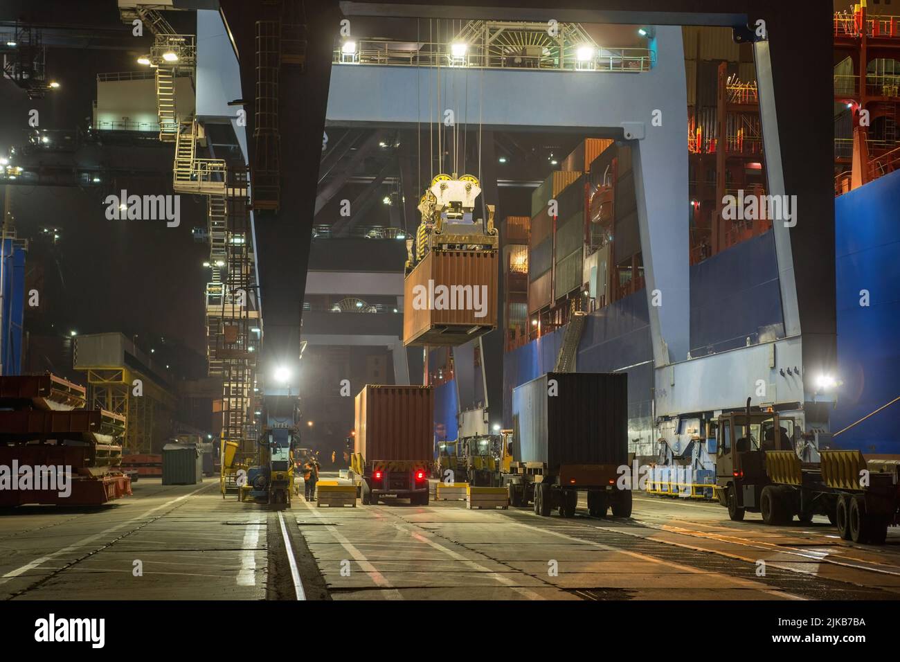 operation of container terminal at night. Unloading container ship at night. Mooring cranes ...