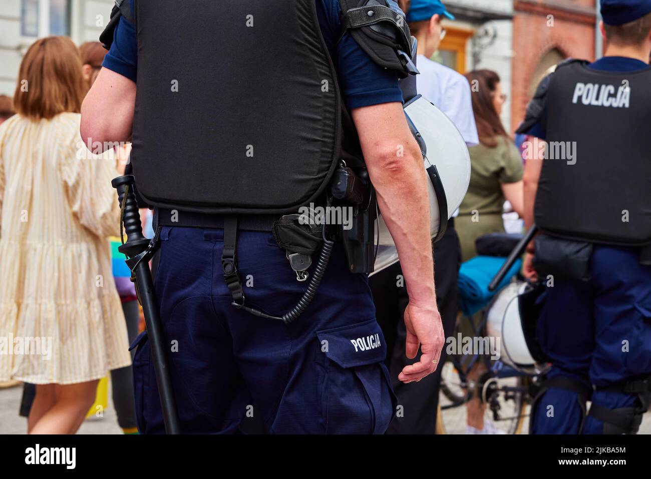 Uniformed policeman with gun and handcuffs keeps order at demonstration on street in Poland ...
