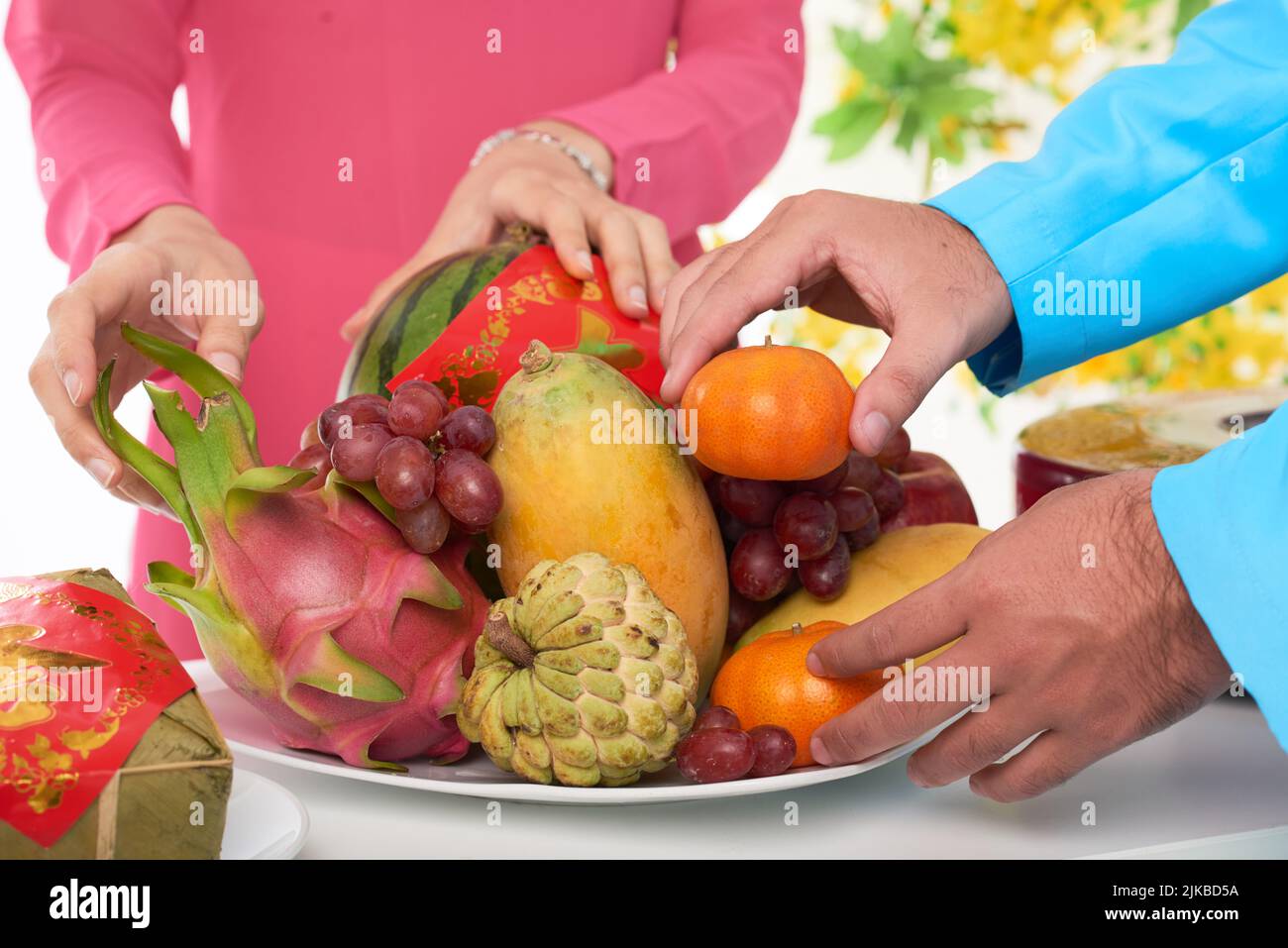 Close-up image of people putting fruits in a dish for Tet Stock Photo ...