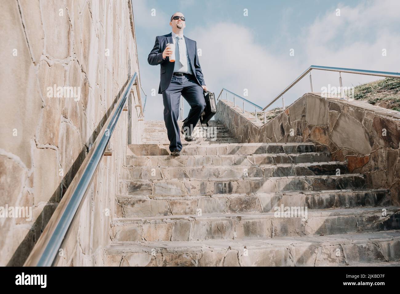 Confident middle age businessman with briefcase walking upstairs. Close ...