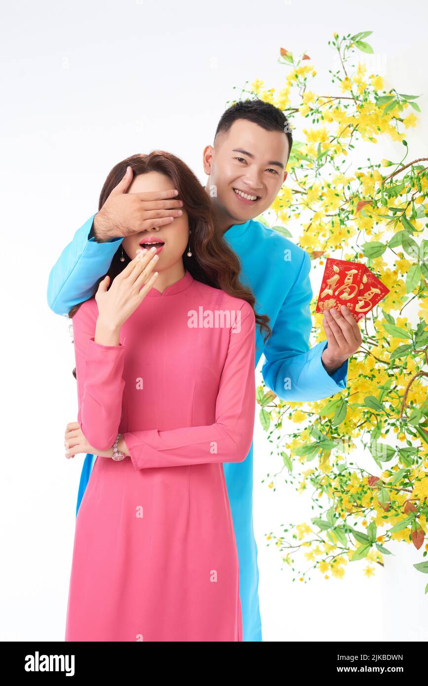 Happy young man covering eyes of his girlfriend to give her lucky money ...