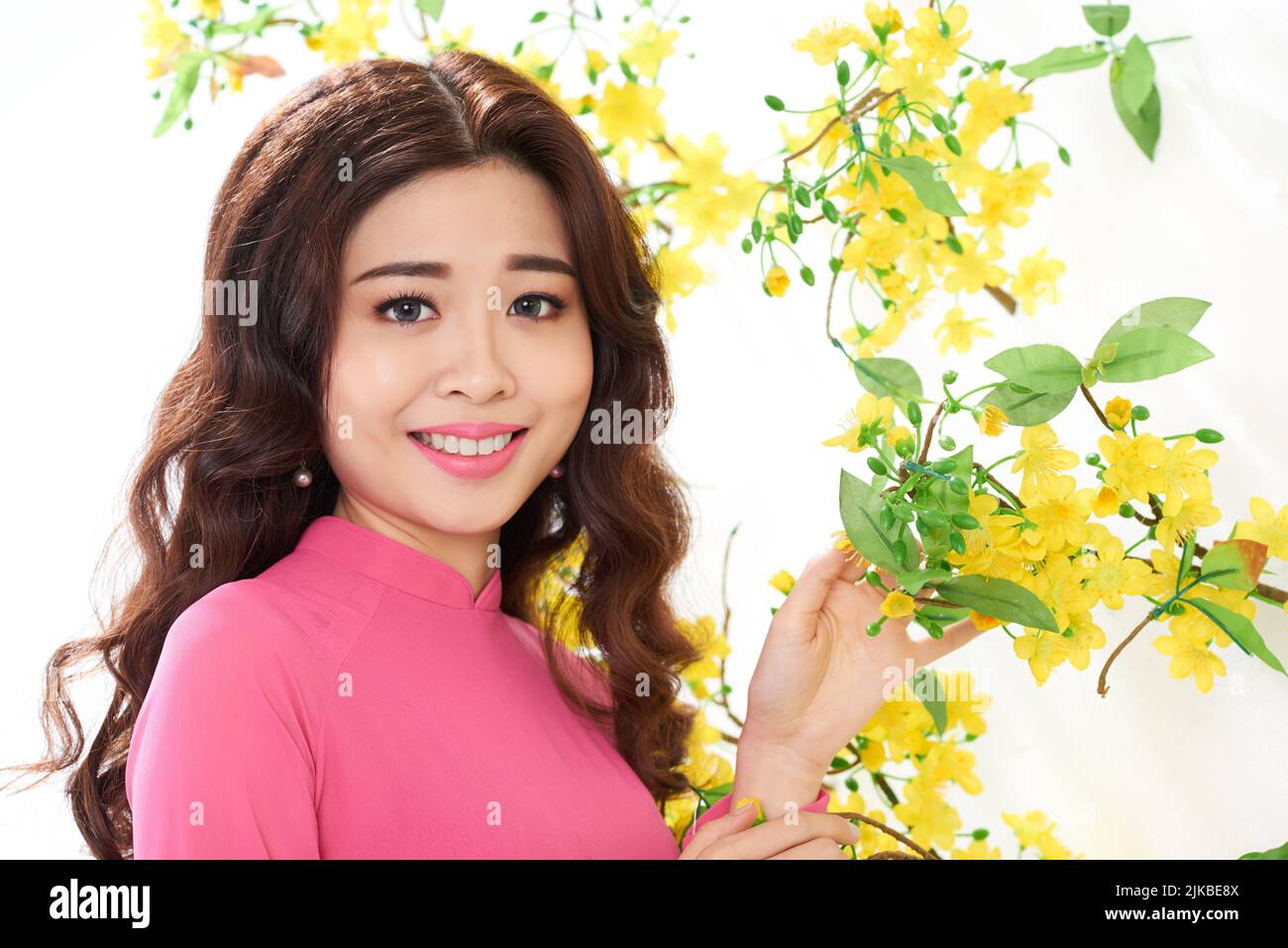 Portrait of beautiful young Asian woman standing next to blooming ...