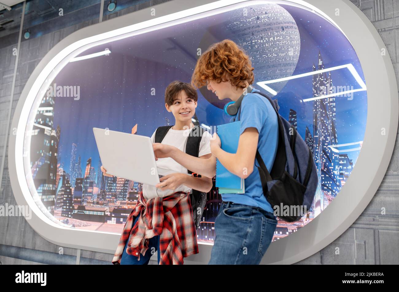 Two friends standing near the window in a modern school Stock Photo - Alamy