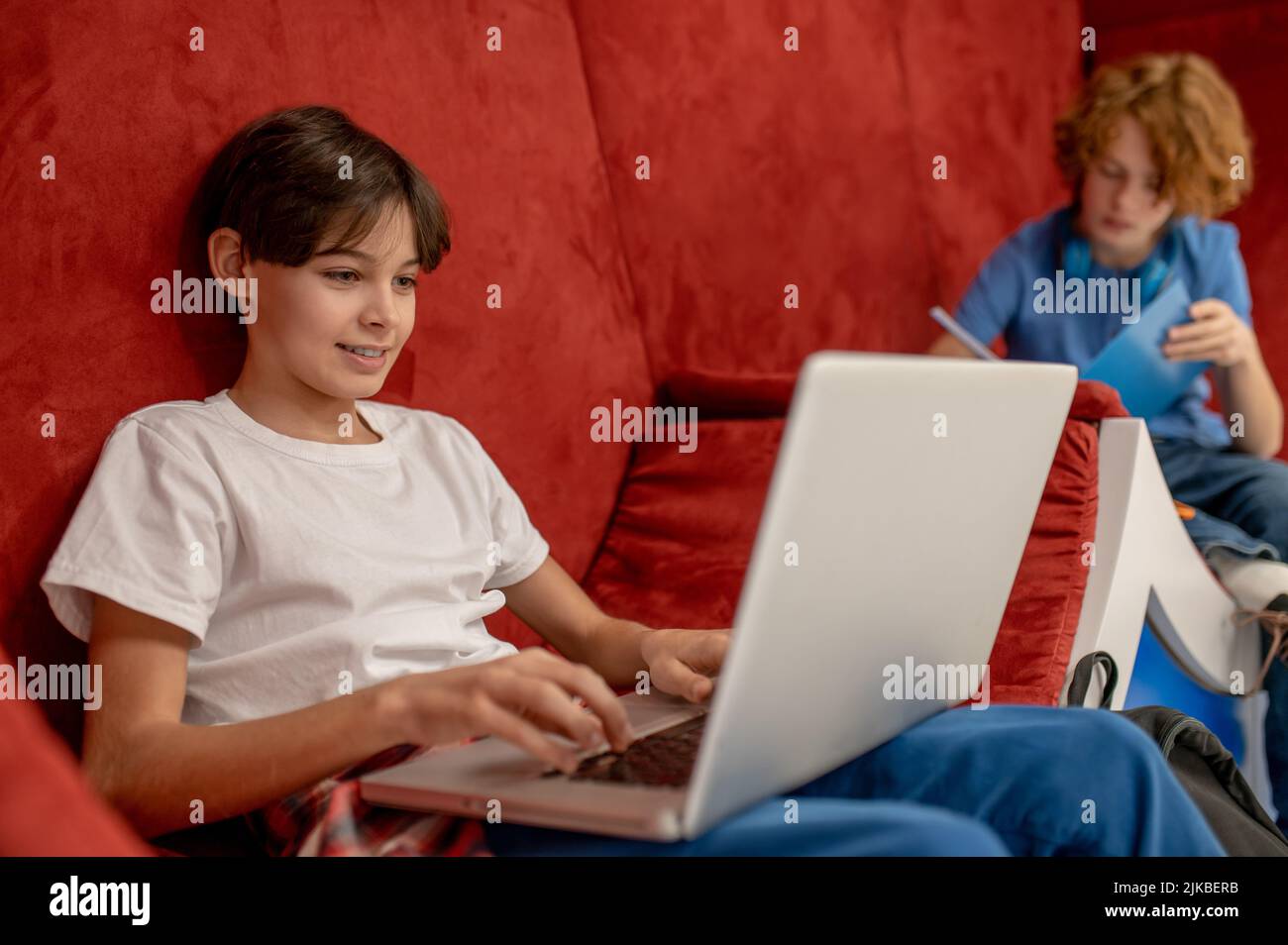 Two school boys feeling comfortable in the lounge zone and doing ...