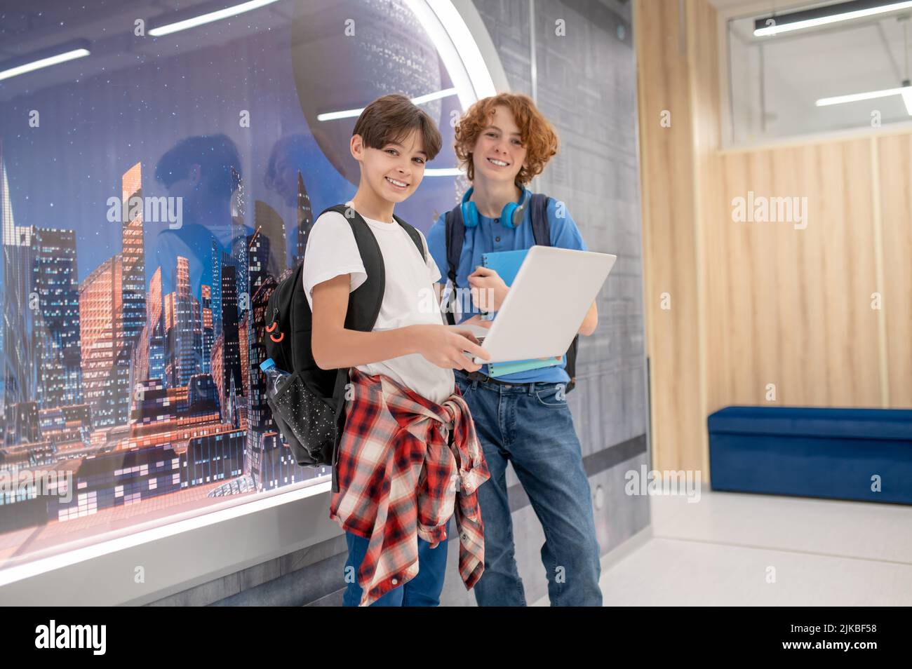 Two friends standing near the window in a modern school Stock Photo - Alamy