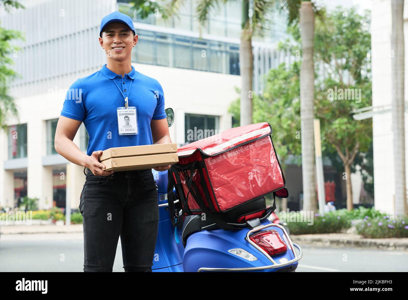 Cheerful handsome young delivery guy holding boxes with hot pizza Stock ...