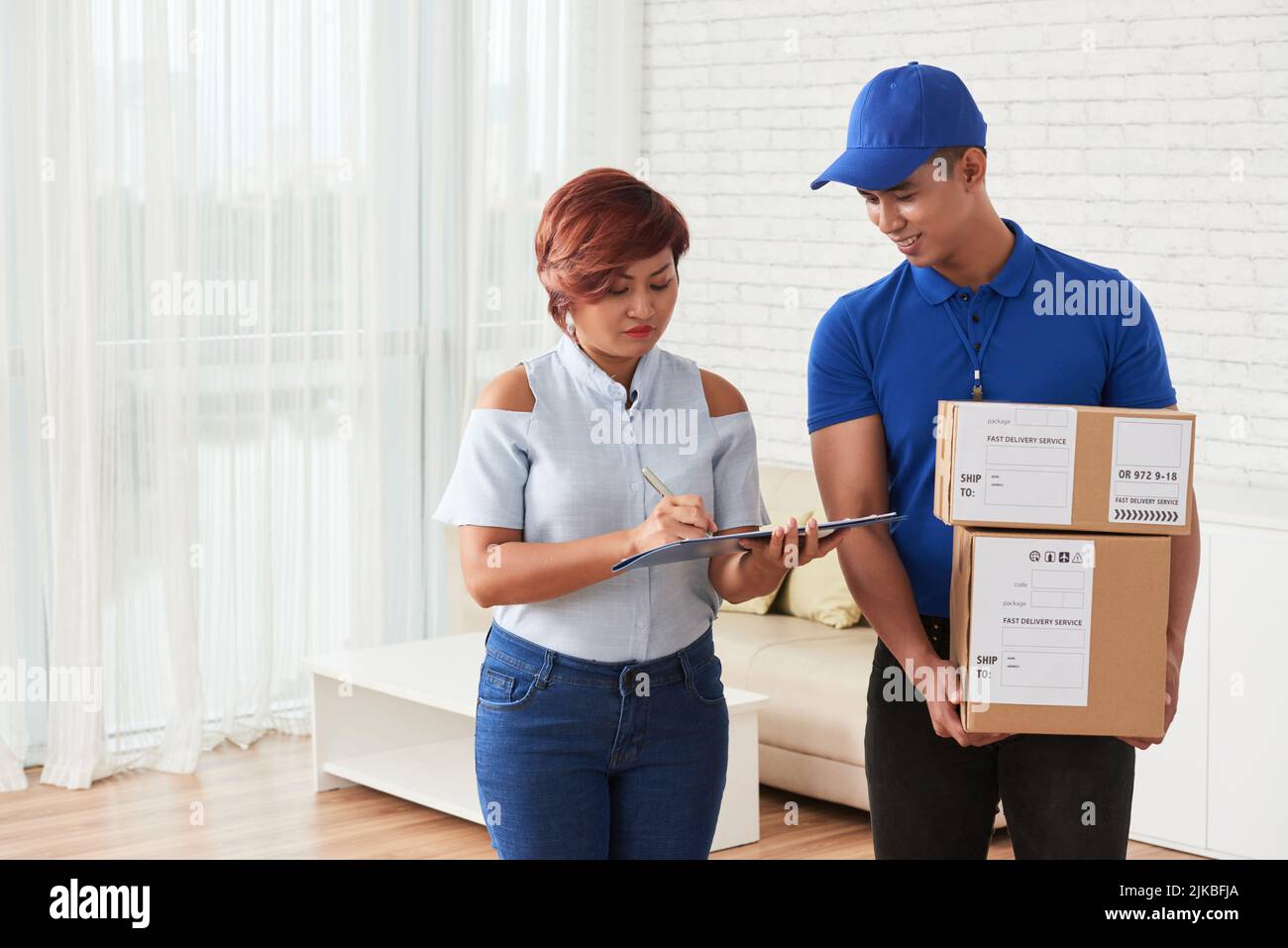 Vietnamese woman signing delivery document after receiving packages ...