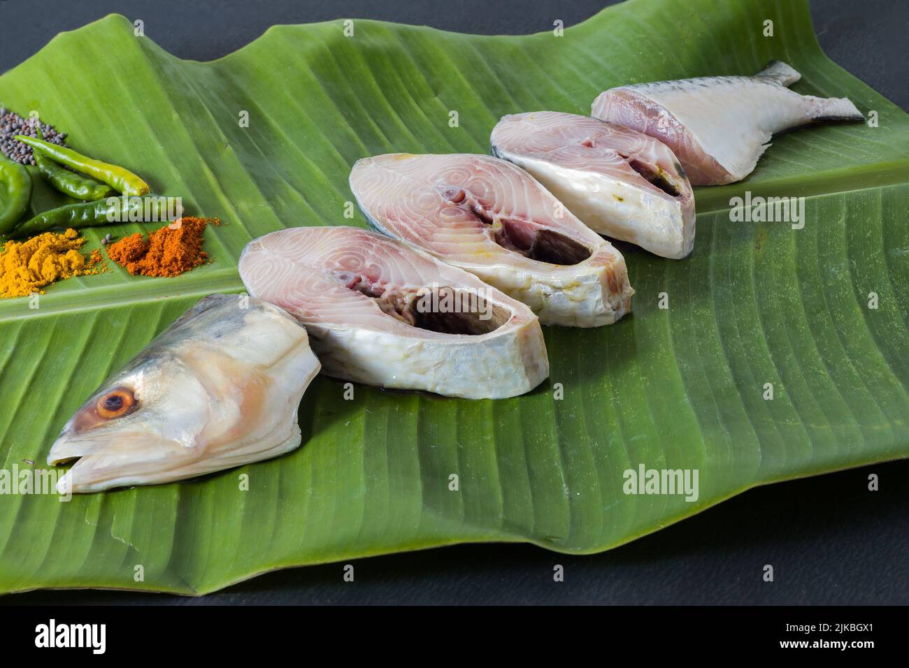 Raw hilsa fish cut into pieces kept on banana leaf for cooking. Shot ...