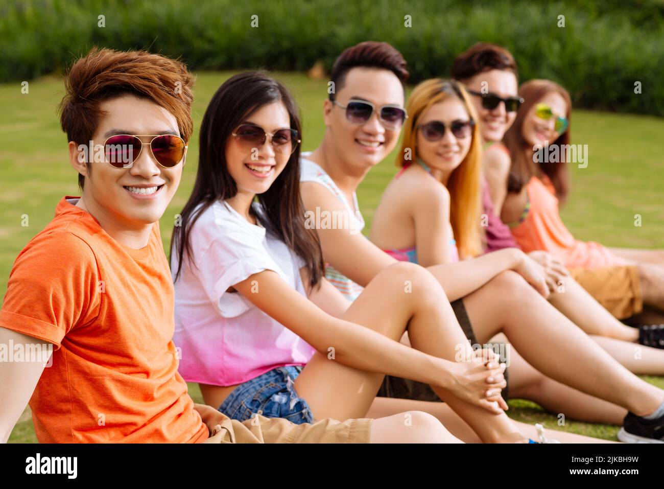 Cheerful young Vietnamese people resting in the park, focus on smiling ...