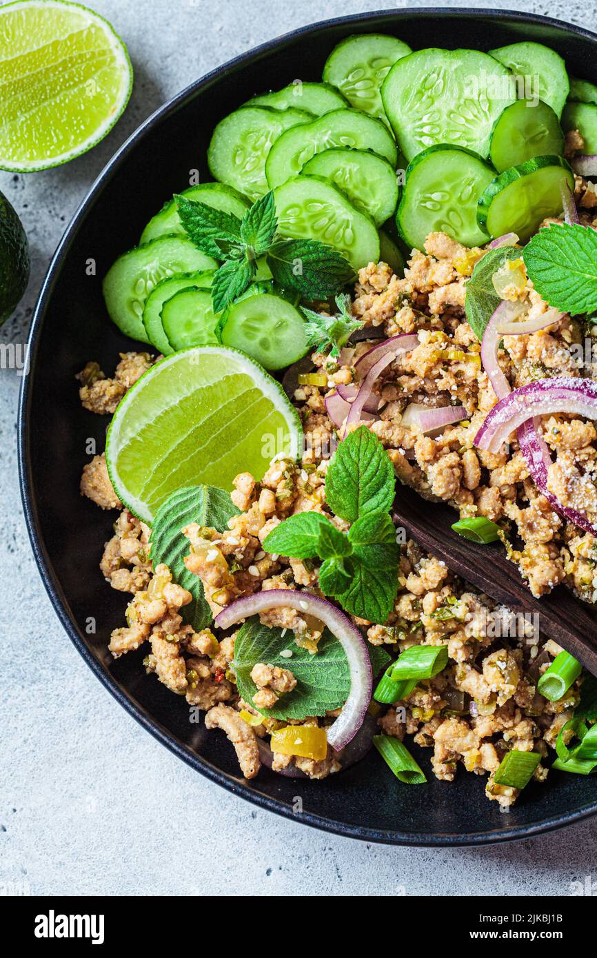 Thai chicken salad larb gai with onion, cucumber and mint in a black ...