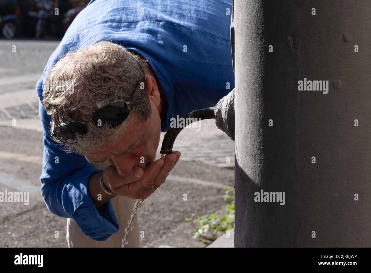 Man drinks clean fresh drinking water from a public drinking fountain ...