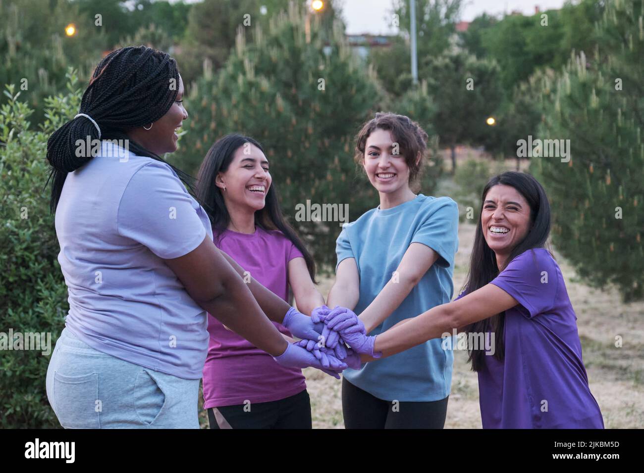 Group of multiracial active women smile and put hands together after ...
