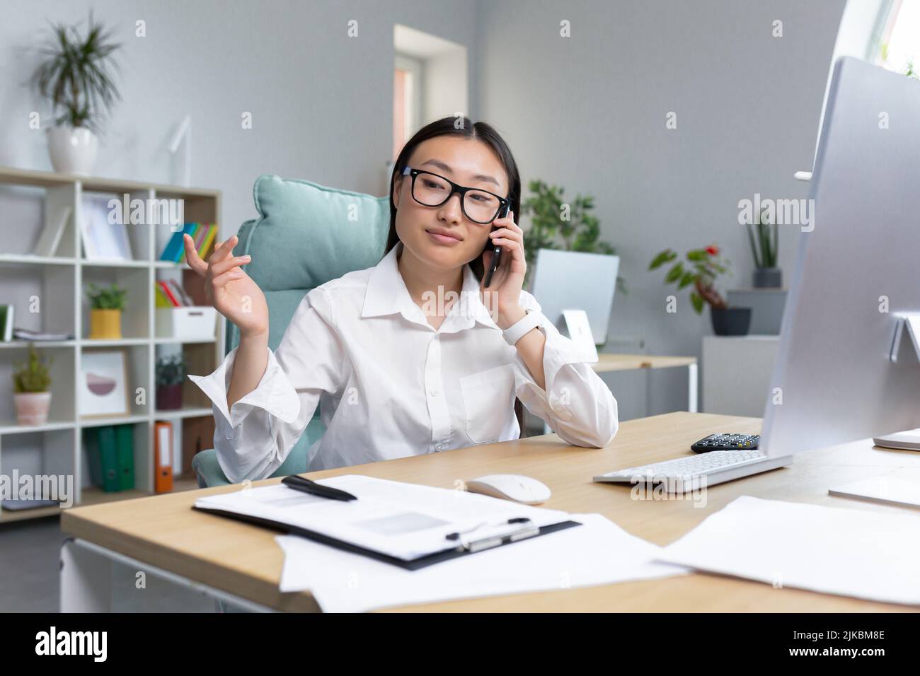 Online sales. A young beautiful Asian woman sales manager sells goods ...