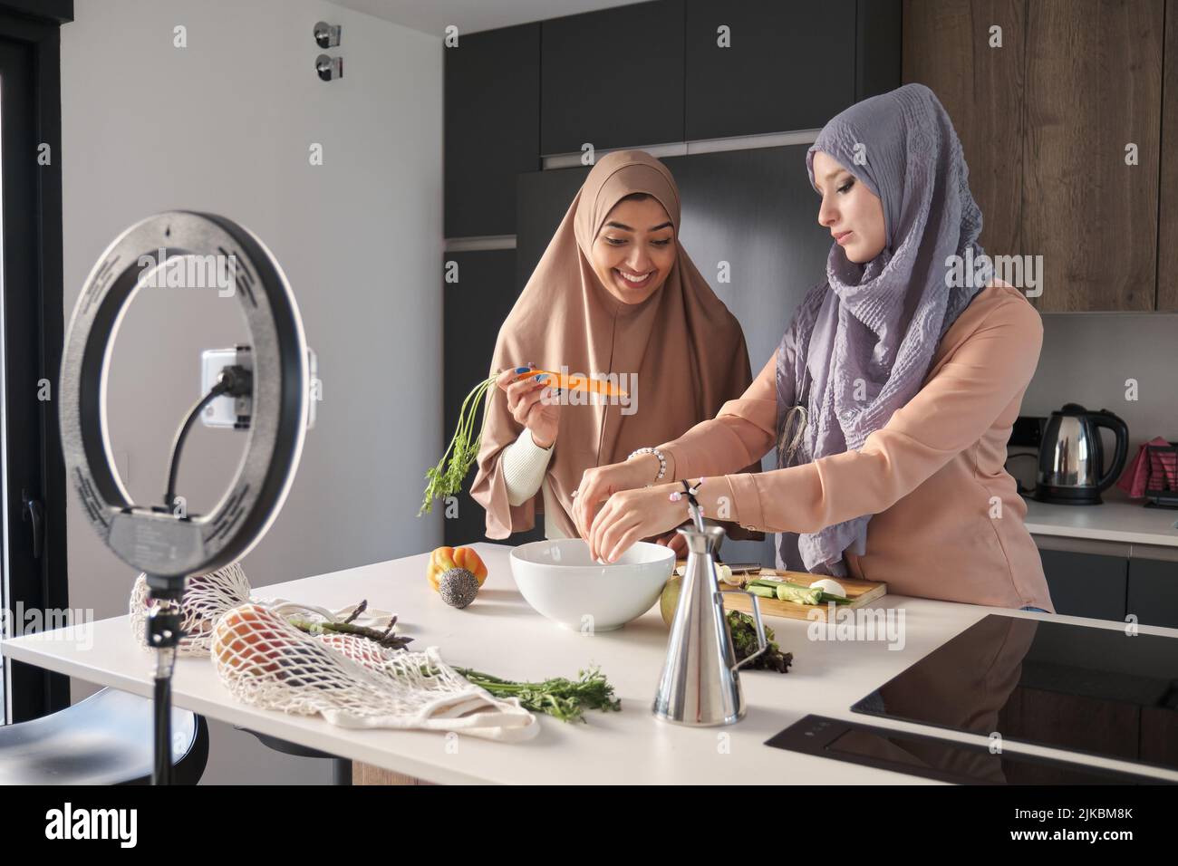 Two muslim food vloggers making a video while prepping vegetables in ...