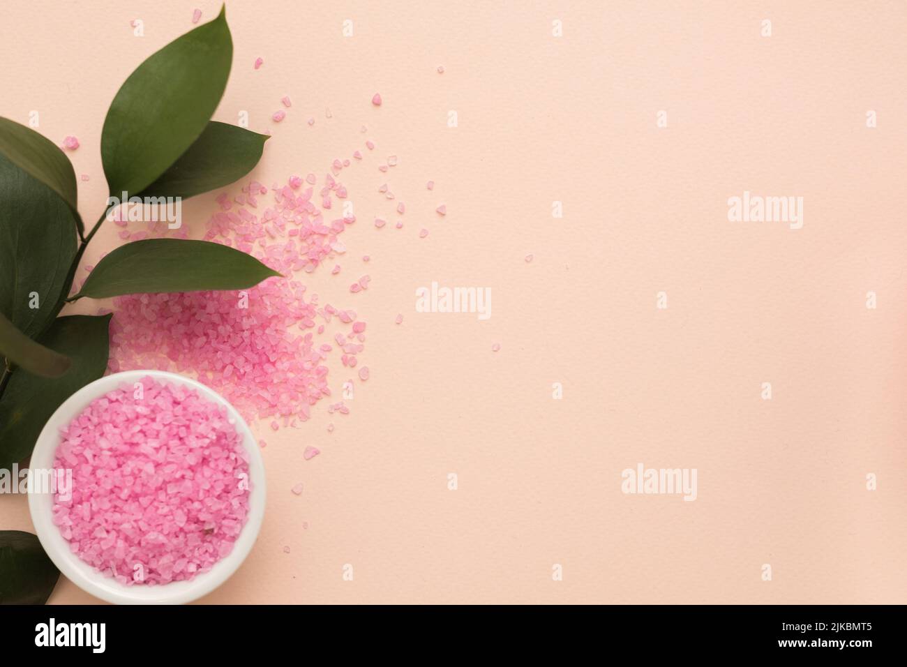 spa therapy pink bath salt leaves peach background Stock Photo - Alamy