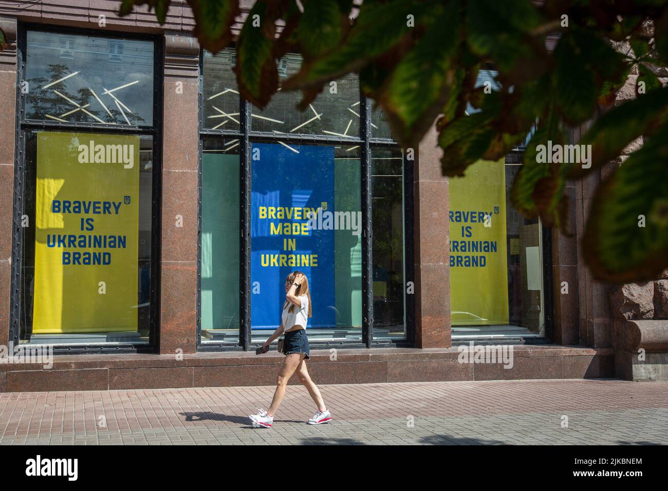 A woman walks by large signs in store windows that read "Bravery is ...