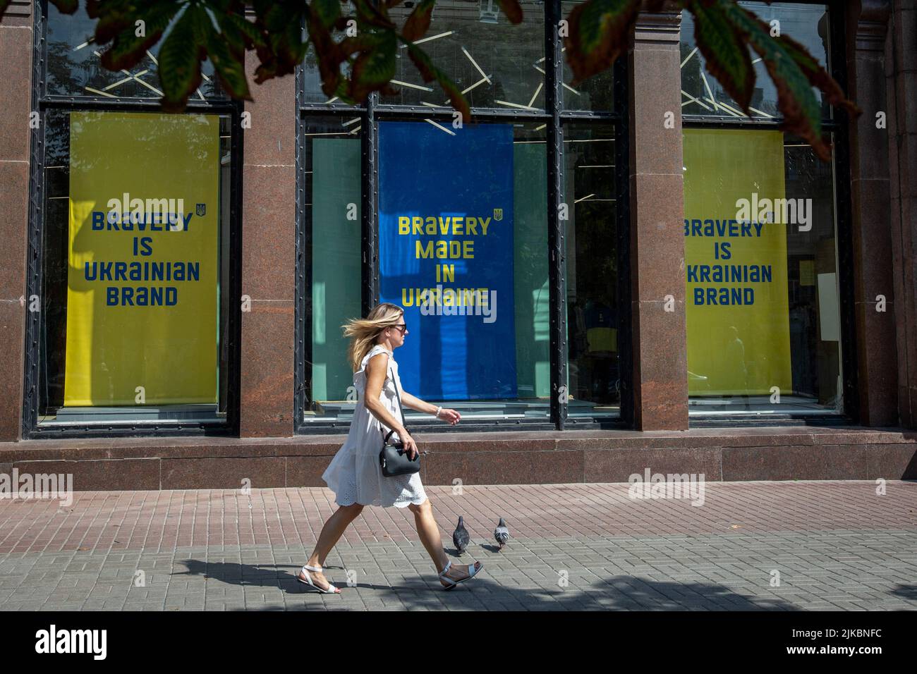 A woman walks by large signs in store windows that read "Bravery is ...