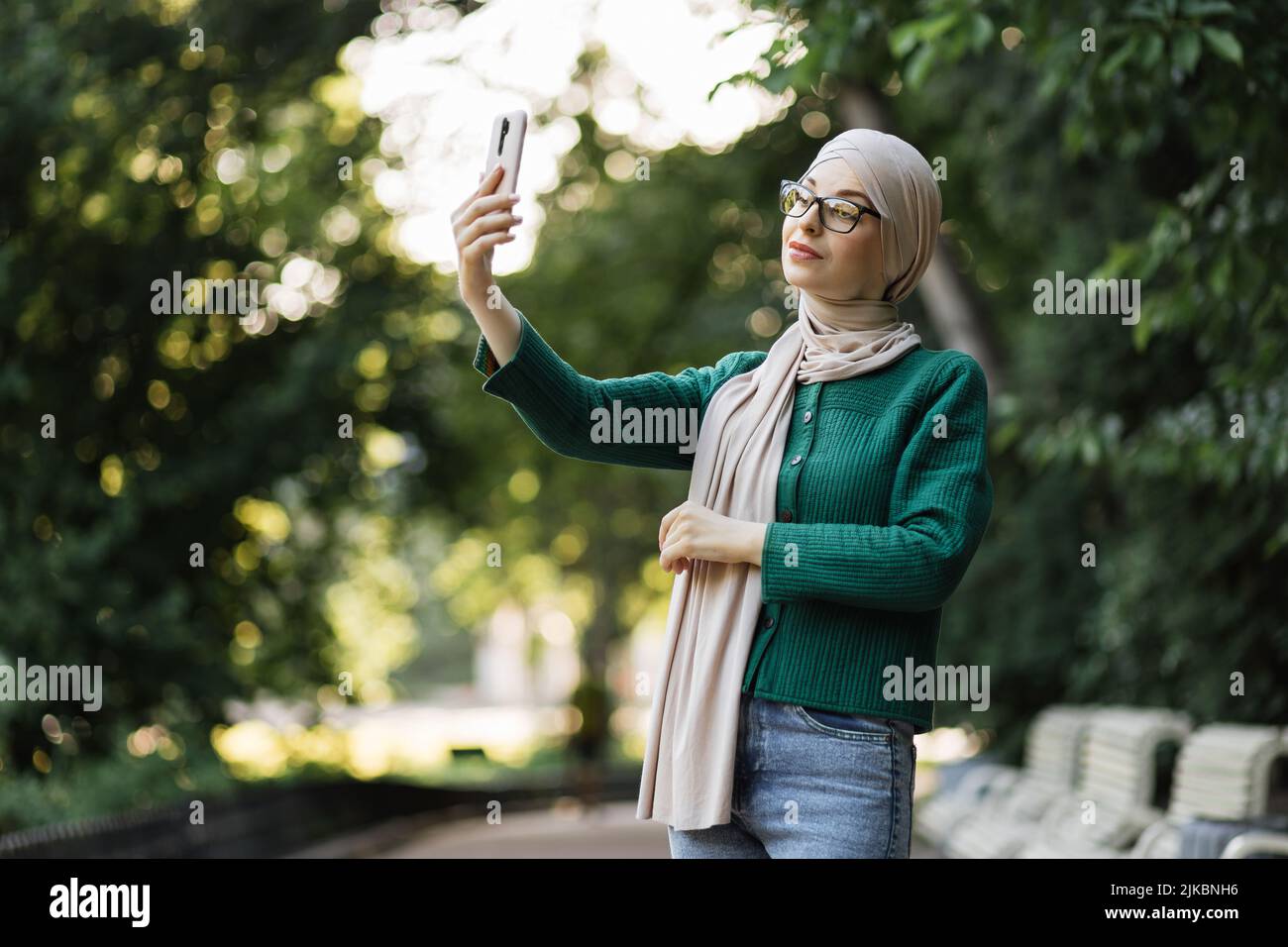 Young Muslim Arab woman in hijab takes a selfie of herself with the ...