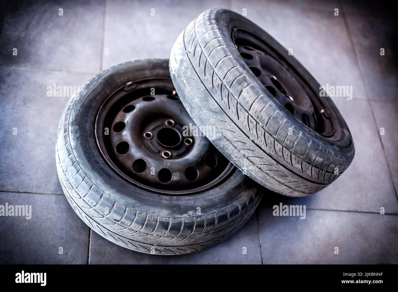 Two used car tires with wheels on the gray floor of the workshop Stock ...