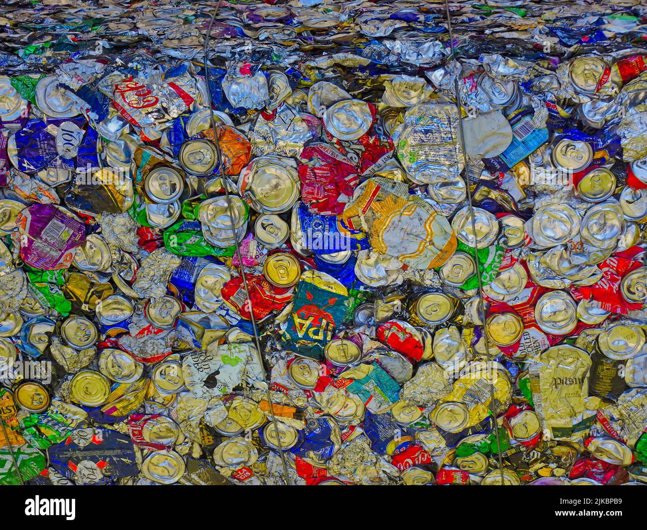 Colourful crushed tin cans compressed into a block, to be sent to the ...