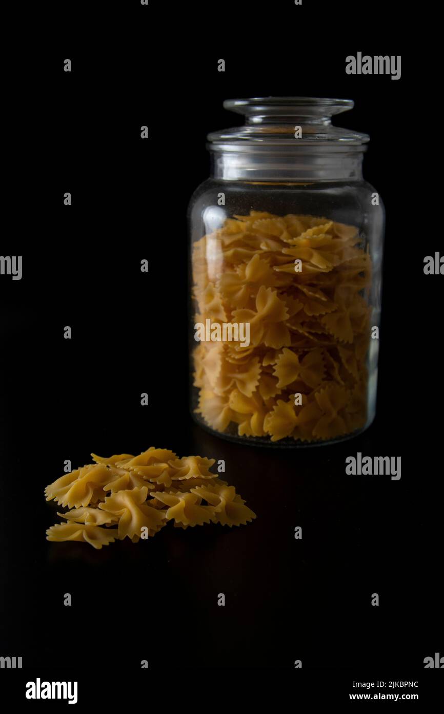 Penne pasta in front of glass jar on the black background Stock Photo ...