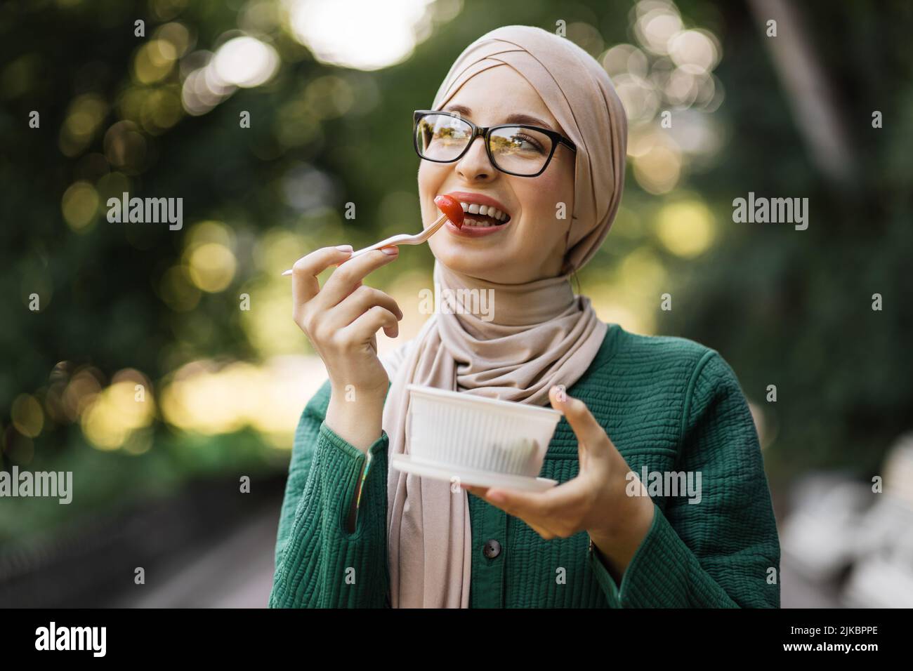 Portrait of a young attractive muslim woman eating salad at the ...