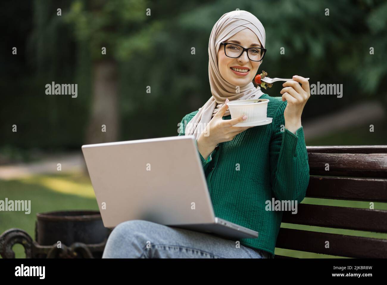 Joyful Muslim Girl In Hijab Eating Healthy Salad On A Break Sitting On