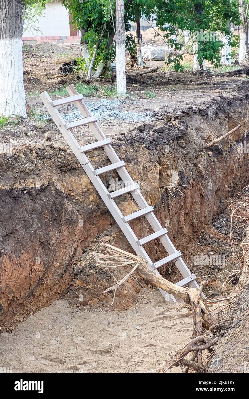 A wooden staircase stands in a deep pit dug for construction work Stock ...
