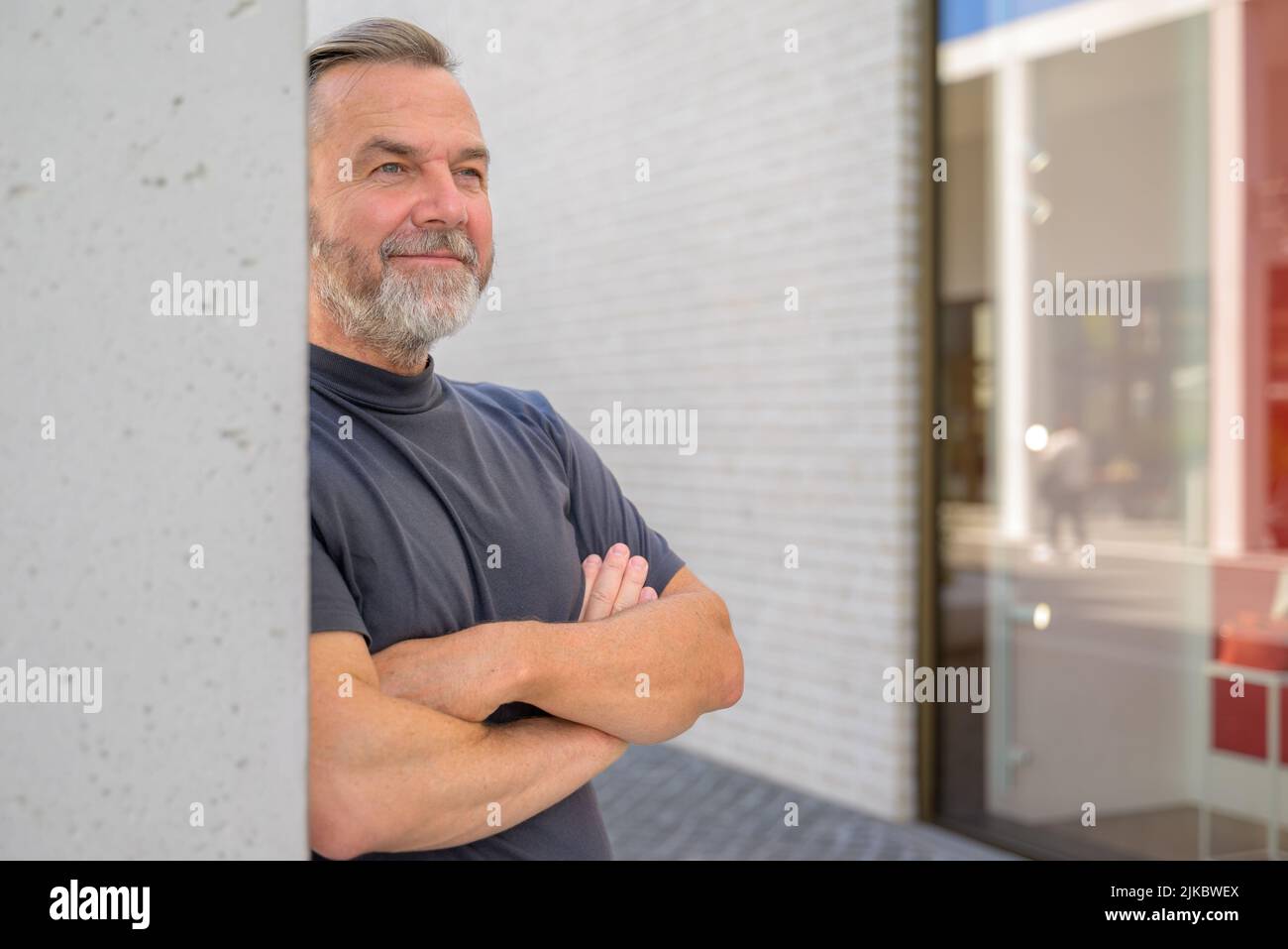 Relaxed middle aged man standing watching with an amused smile as he ...