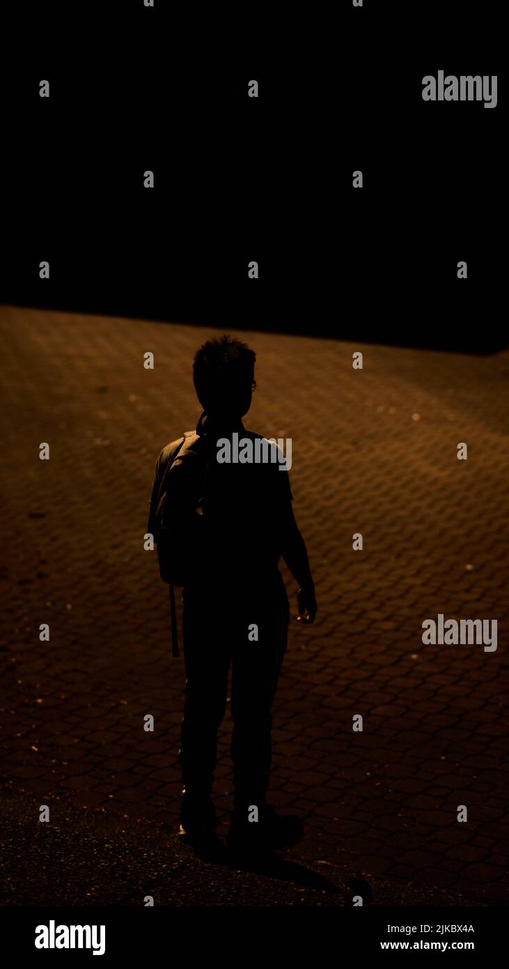 Vertical shot of silhouette of young man walking along the patterns of ...