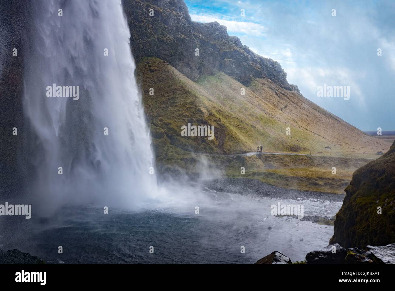 A mesmerizing view of the huge Skogafoss waterfall with tourists in ...