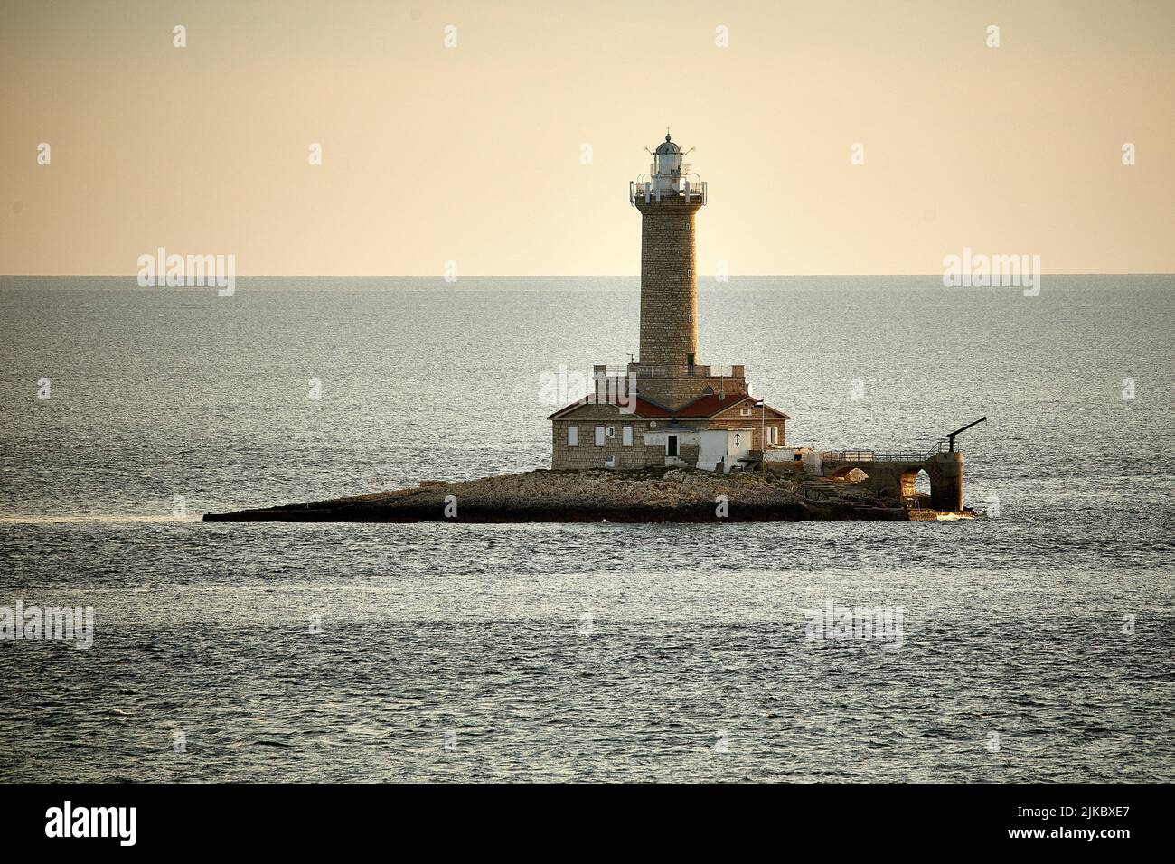 A lighthouse's view in the middle of the sea during sunset Stock Photo ...