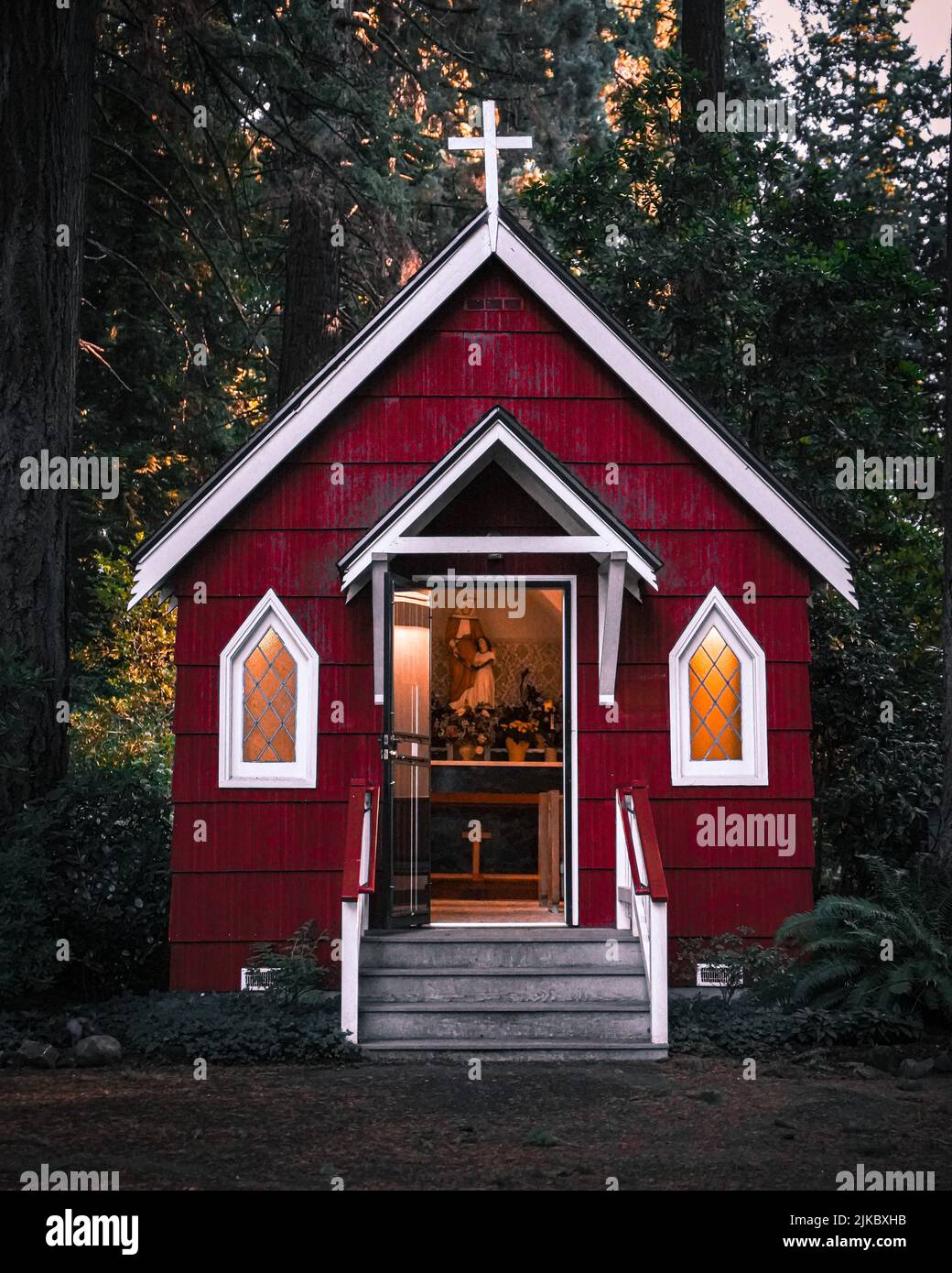 The exterior of chapel with cross on the top and trees in the ...