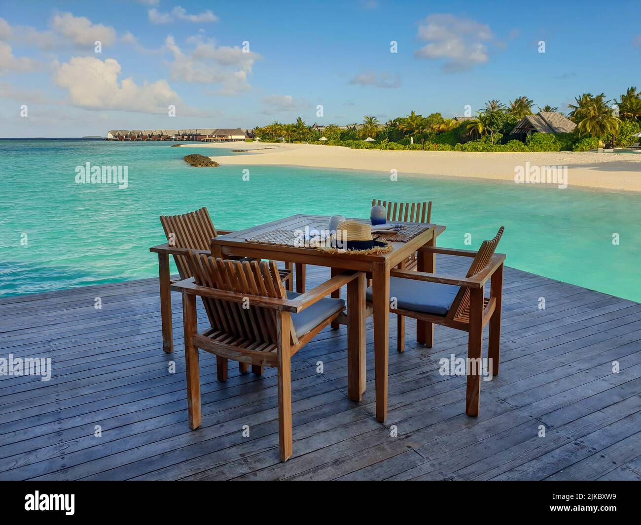 Wooden table and chairs on the terrace overlooking the beach and the ...
