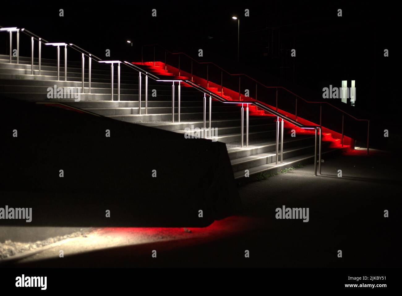 A modern staircase with lights installed in its handrails at night ...