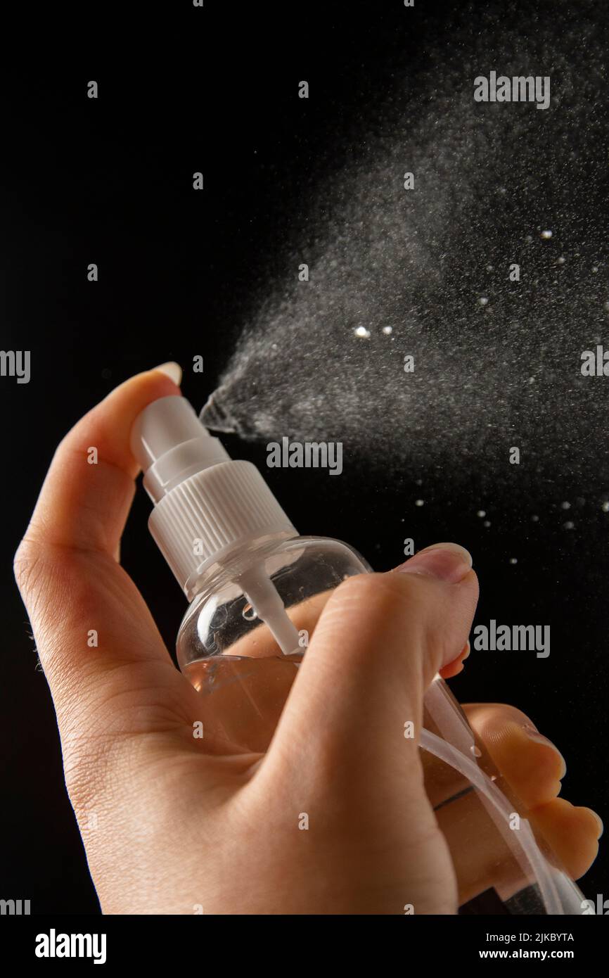 Hand holding atomizer and sprinkling in the air Stock Photo - Alamy