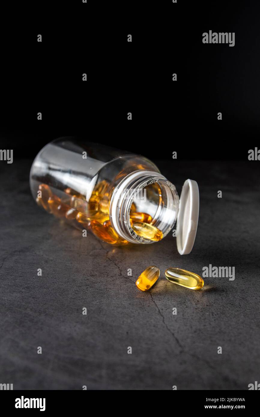 Omega 3 caps out of the container on a dark background Stock Photo - Alamy