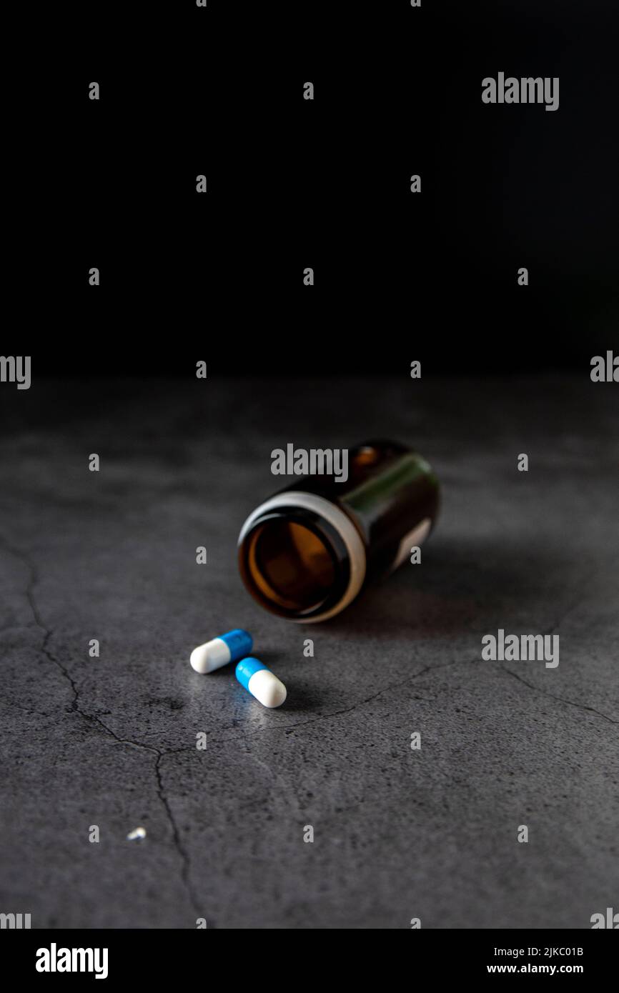 Painkiller pills out of the container on a dark background Stock Photo ...