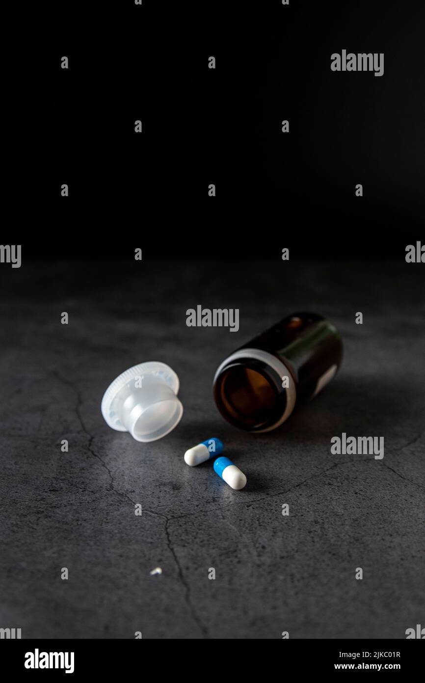 Painkiller pills out of the container on a dark background Stock Photo ...