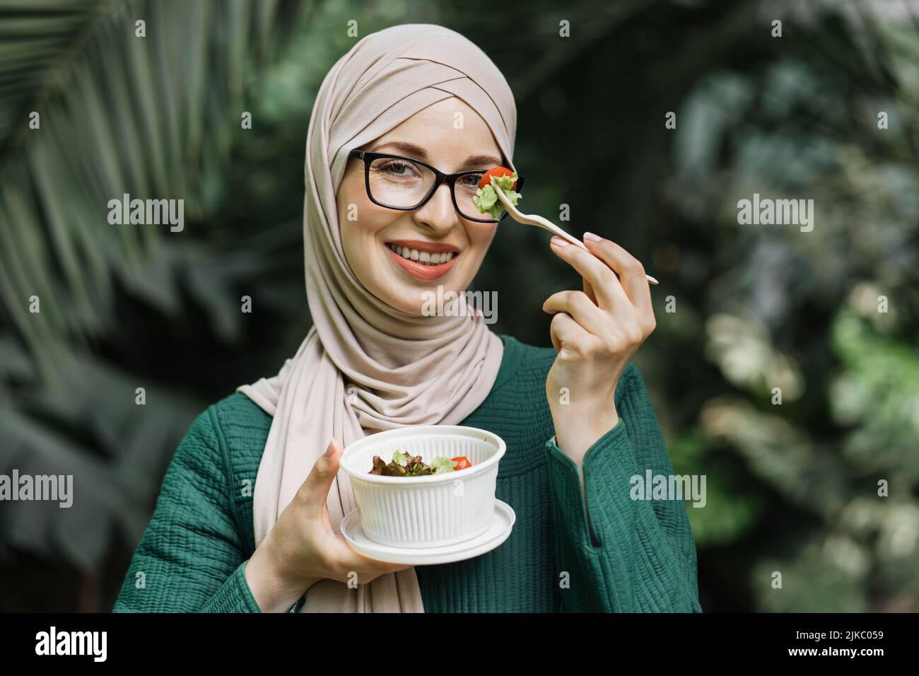 Happy positive muslim business woman eating healthy salad on a break ...