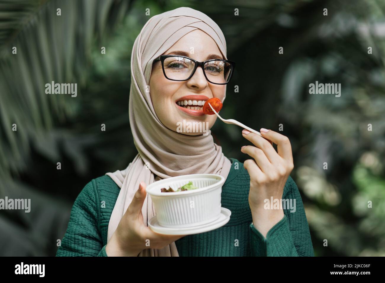 Portrait of smiling muslim business woman eating healthy salad while ...