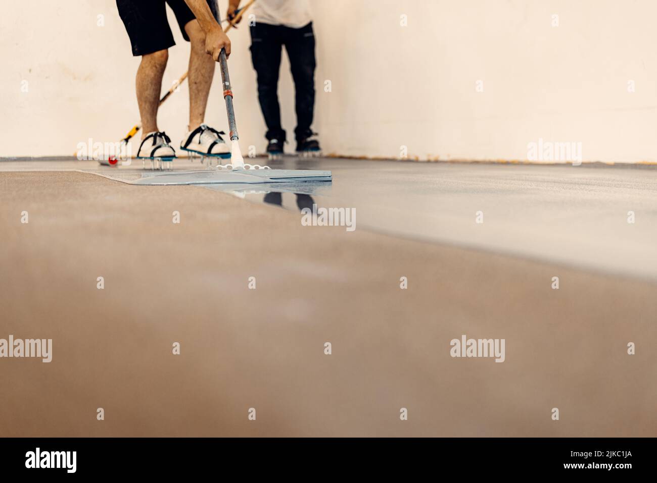 A closeup shot of worker applying floor primer with a special tool ...