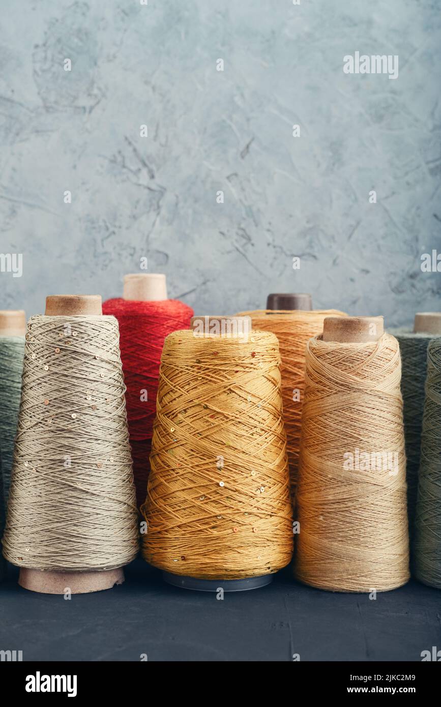 Set of colored yarn for knitting on cone on light background, with copy ...