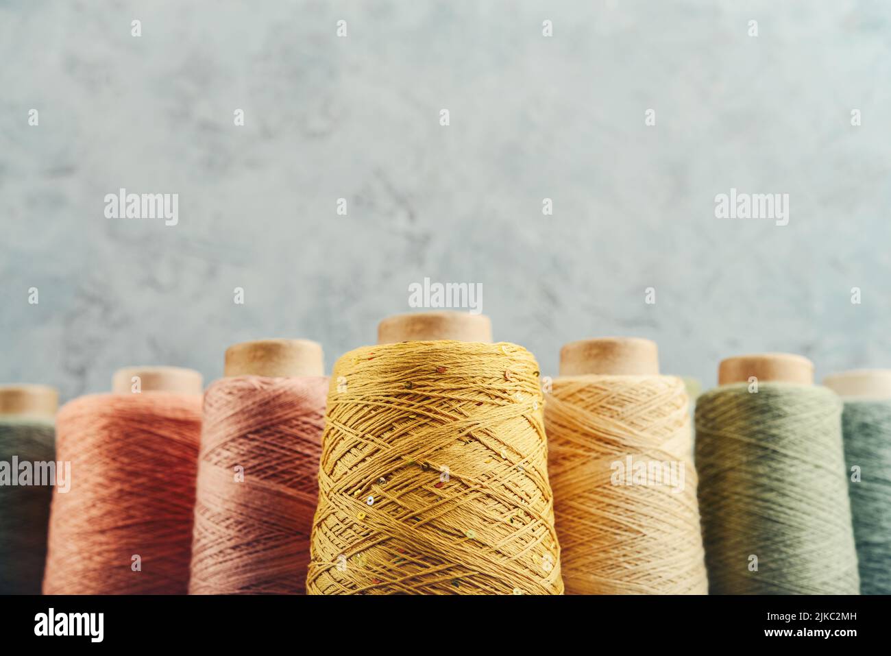 Set of colored yarn for knitting on cone on light background, with copy ...