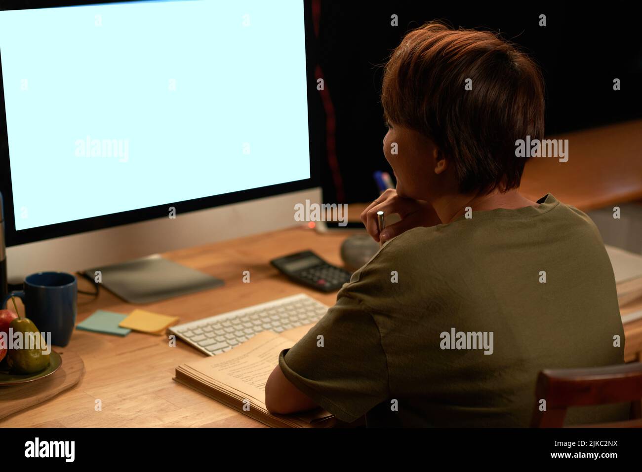 Adult female student looking at computer monitor while studying at home ...