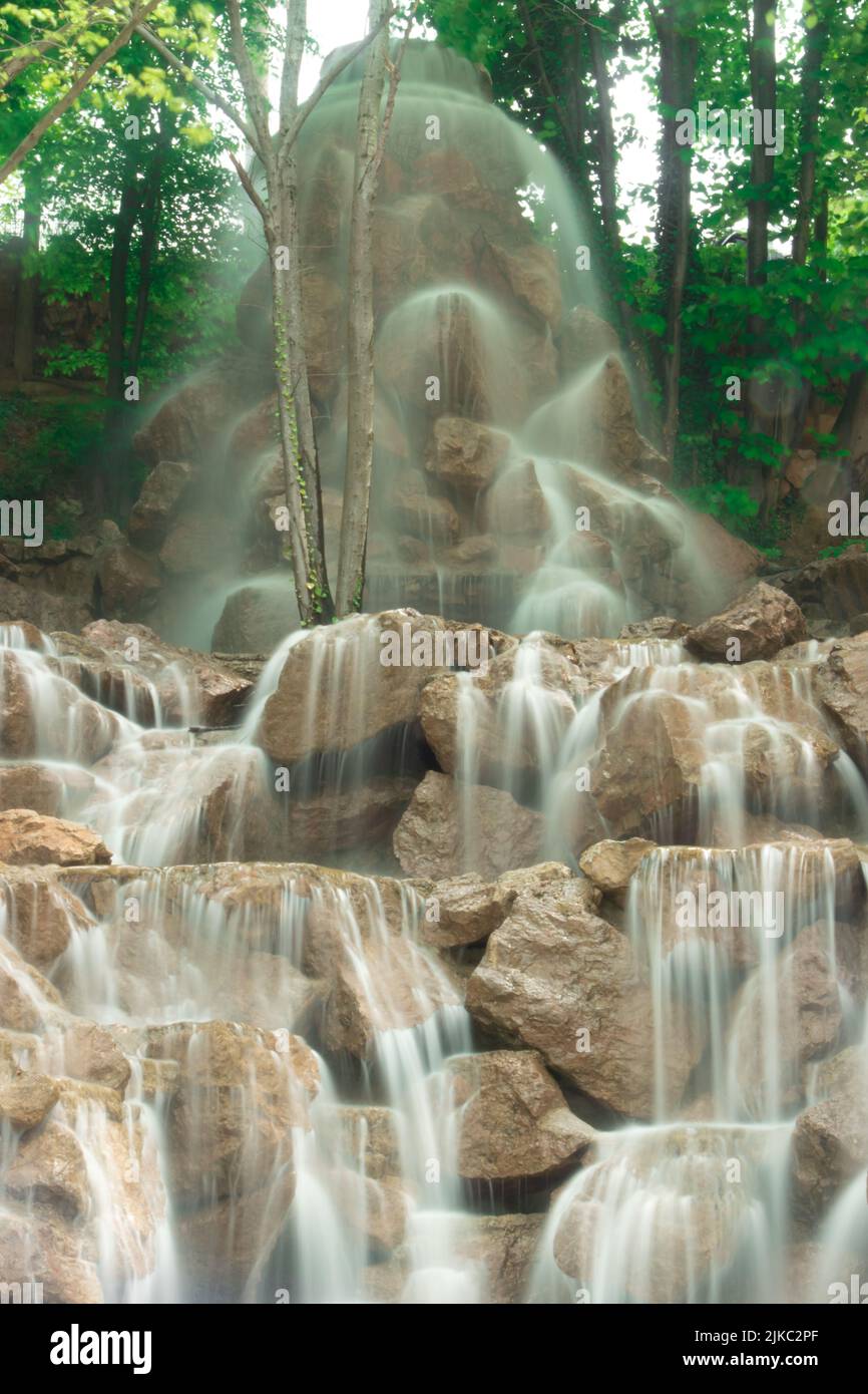 A long exposure shot of a beautiful waterfall with rocks surrounded ...