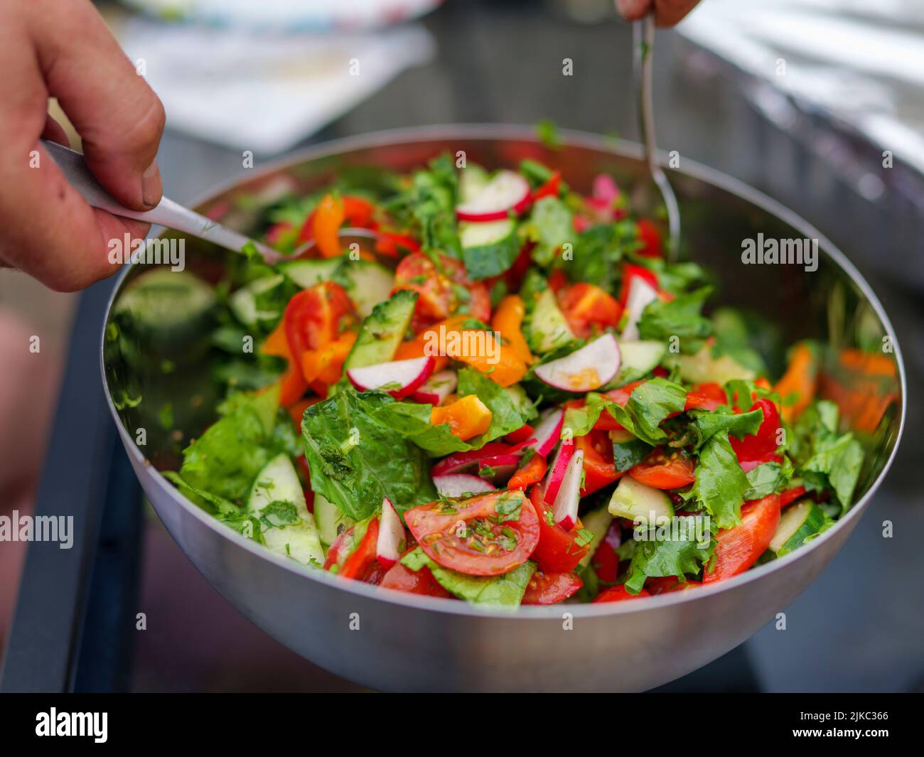 Selective focus of fresh chopped spring salad, man mixing salad ...