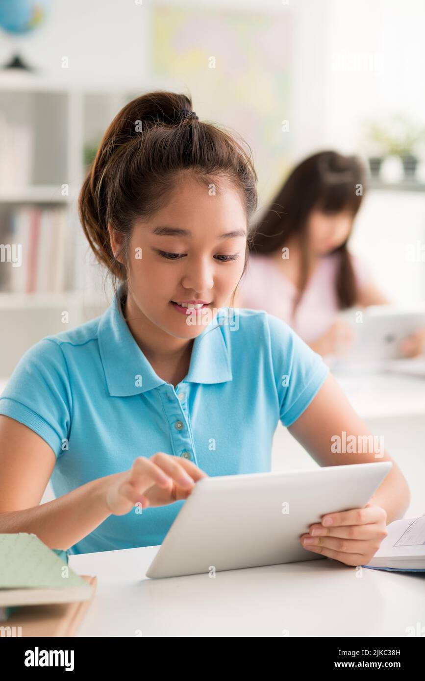 Waist-up portrait of curious Vietnamese pupil with ponytail using ...